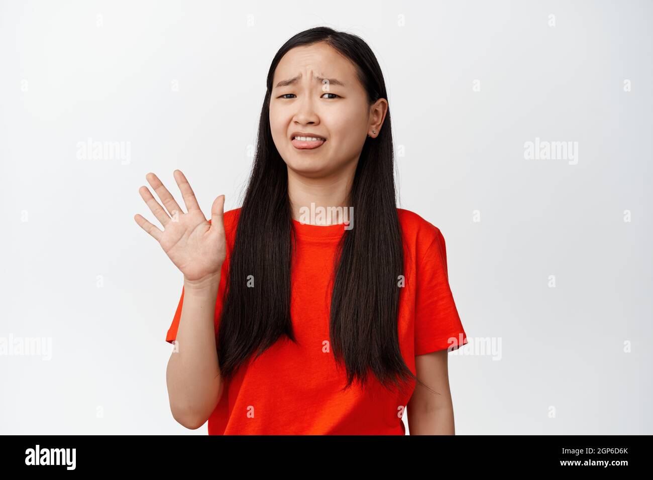 Funny asian girl rejecting something disgusting, shows tongue and wave ...