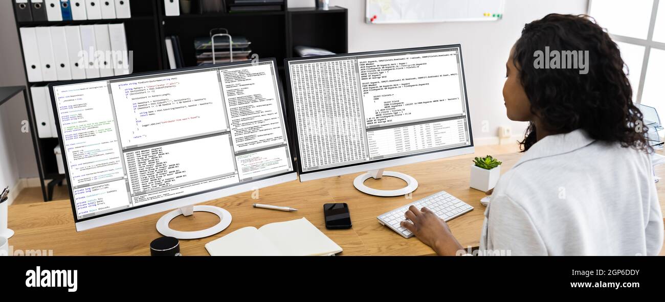 African Coder Using Multiple Computer Screens In Office Stock Photo - Alamy