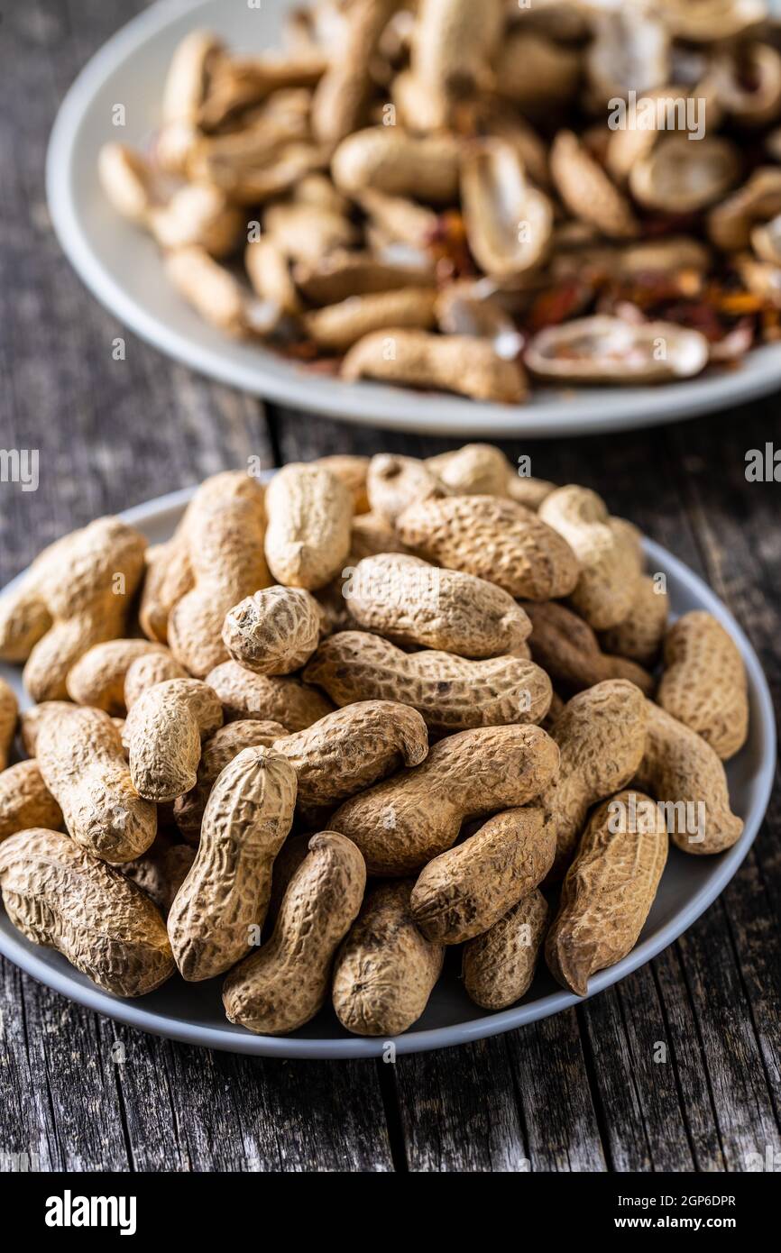 Roasted peanuts. Tasty groundnuts on plate on wooden table Stock Photo ...