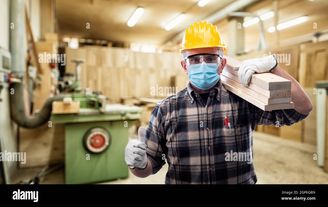 Carpenter worker at work in the carpentry workshop wears surgical mask ...