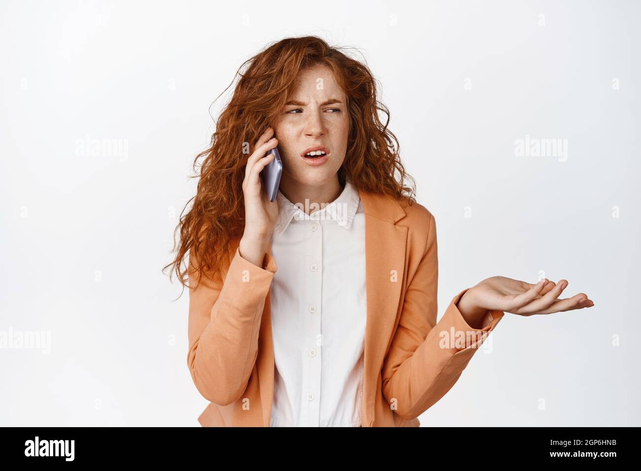Annoyed businesswoman looking confused on phone call, standing in suit ...