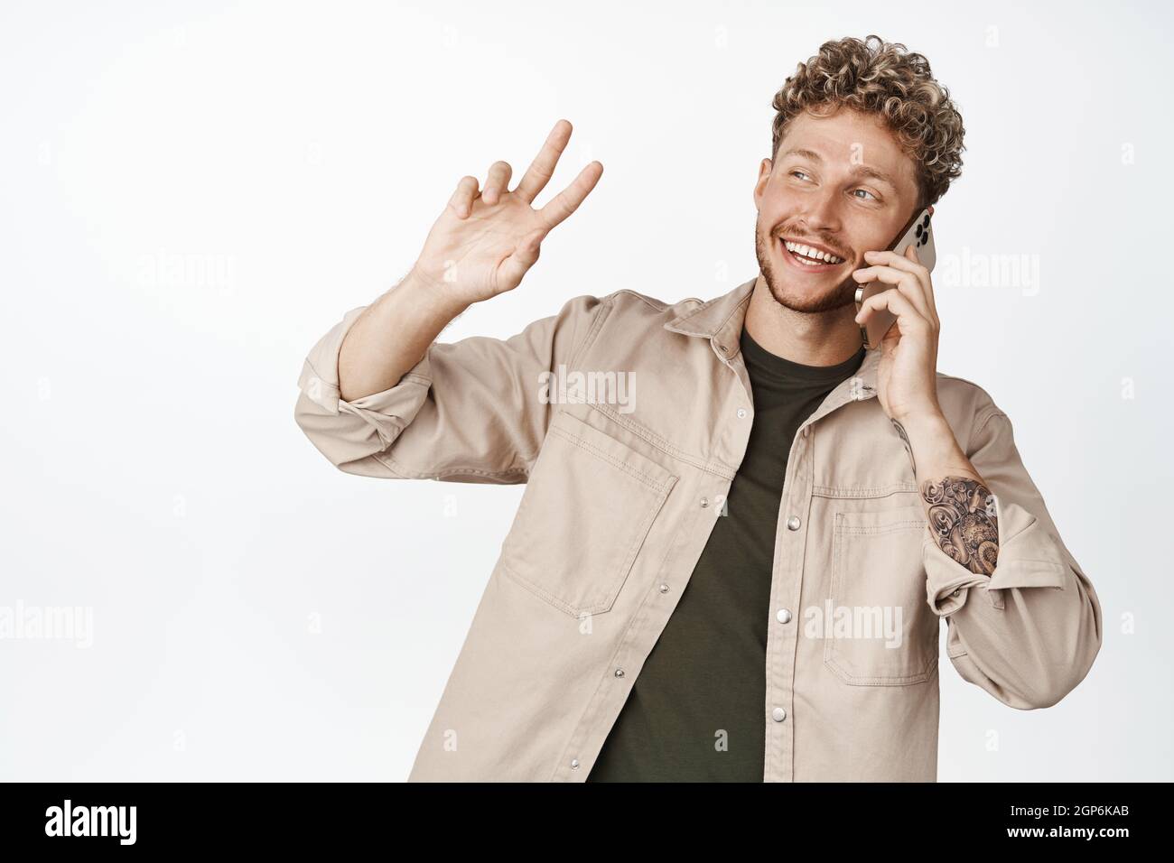 Handsome modern blond guy talking on mobile phone and saying hello to ...