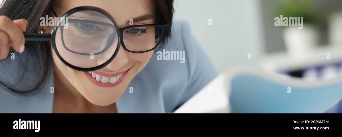 Portrait of young beautiful woman examining documents through ...