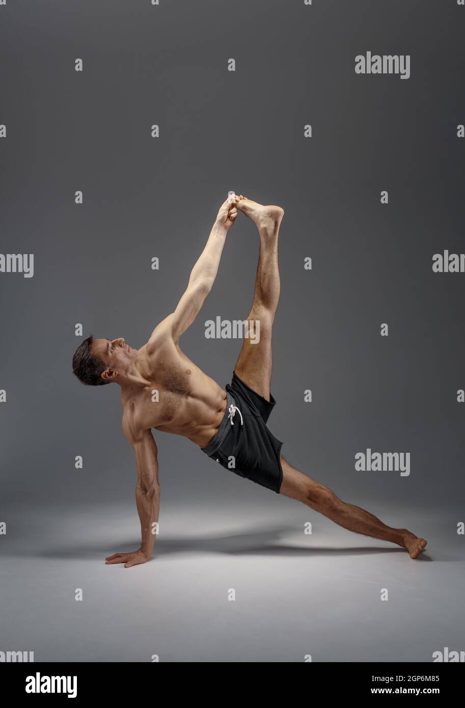 Athletic yoga doing stretching exercise in studio, grey background ...