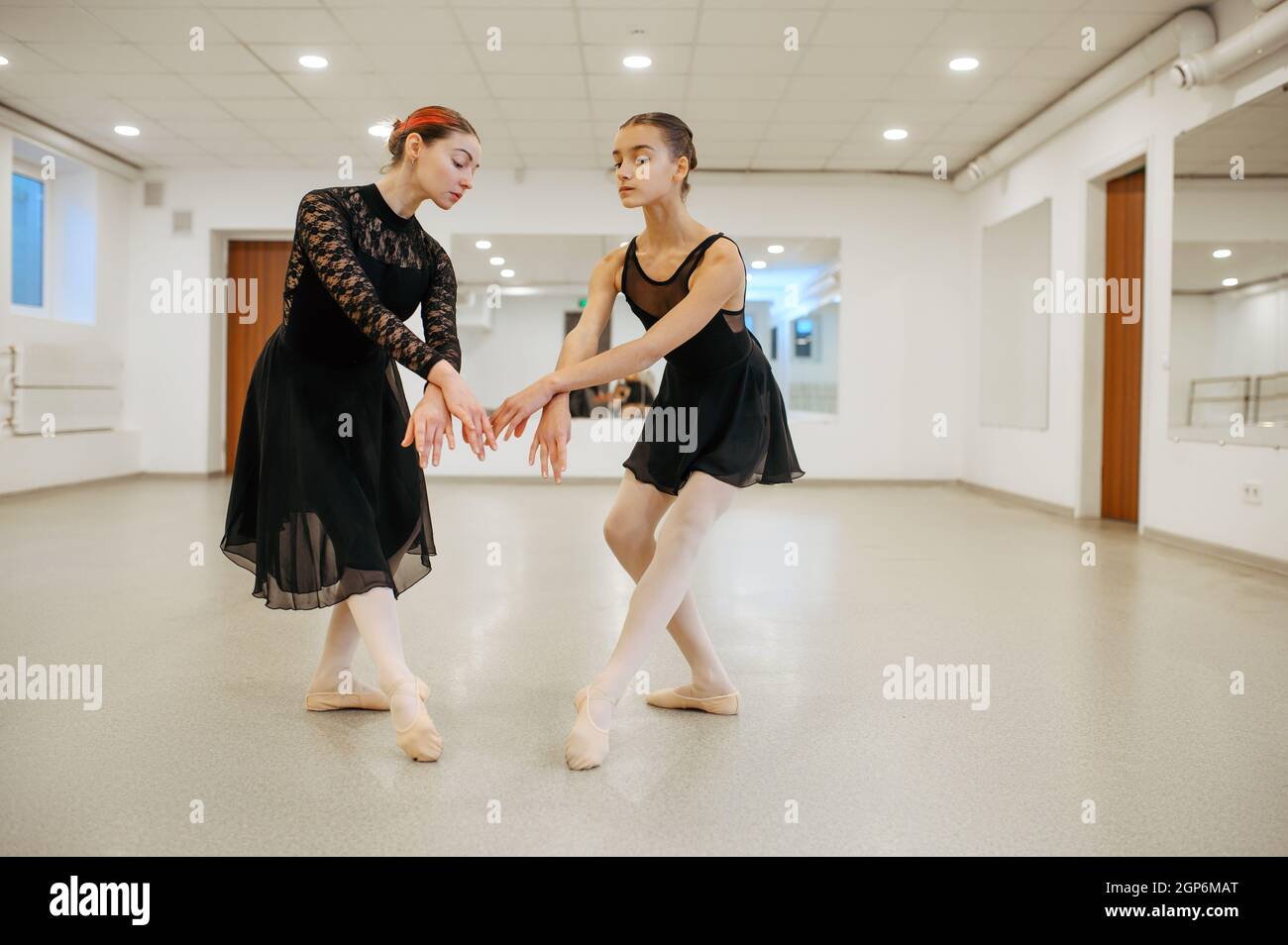 Teacher rehearsing with young ballerina in class. Ballet school, female ...