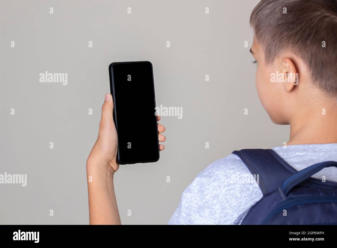 Teenage boy holding cell phone, looking at screen, reading, watching ...