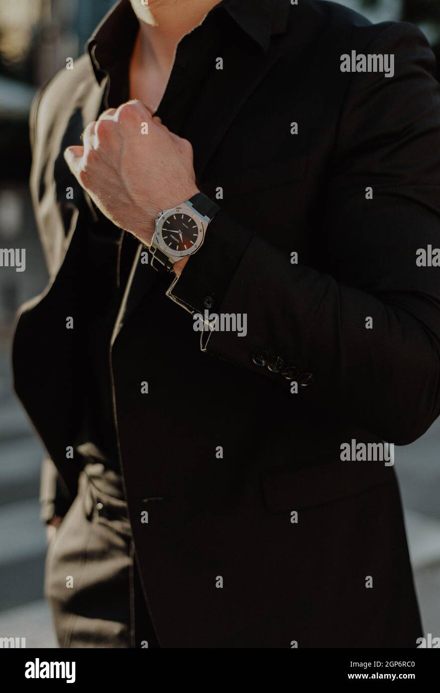 Man wearing a black suit and a watch Stock Photo - Alamy