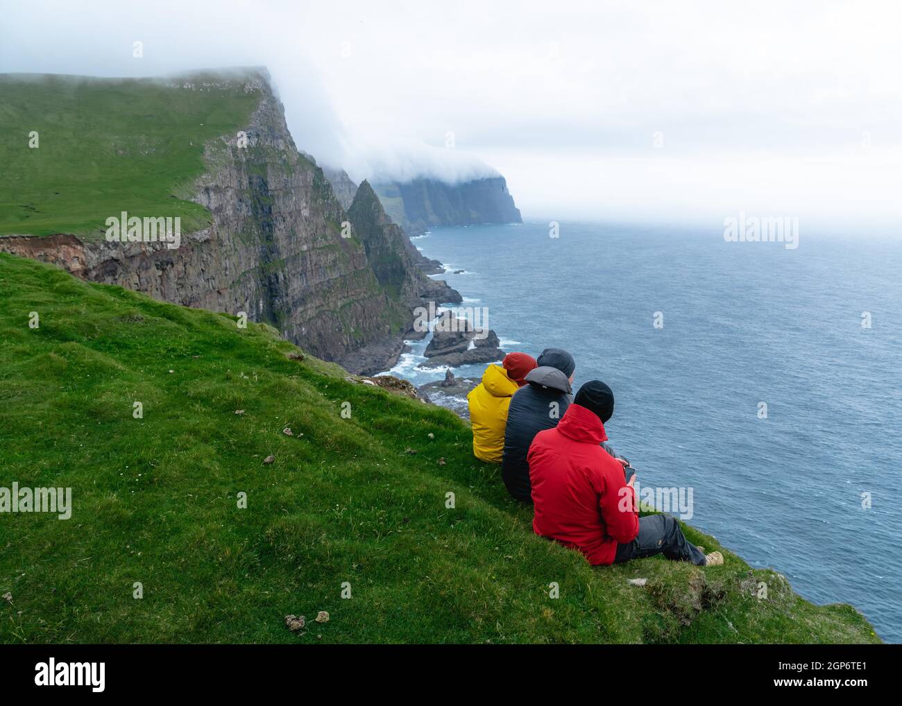 3 Walkers sitting overlooking Beinisforo Cliffs, Sandvik, Suduroy ...