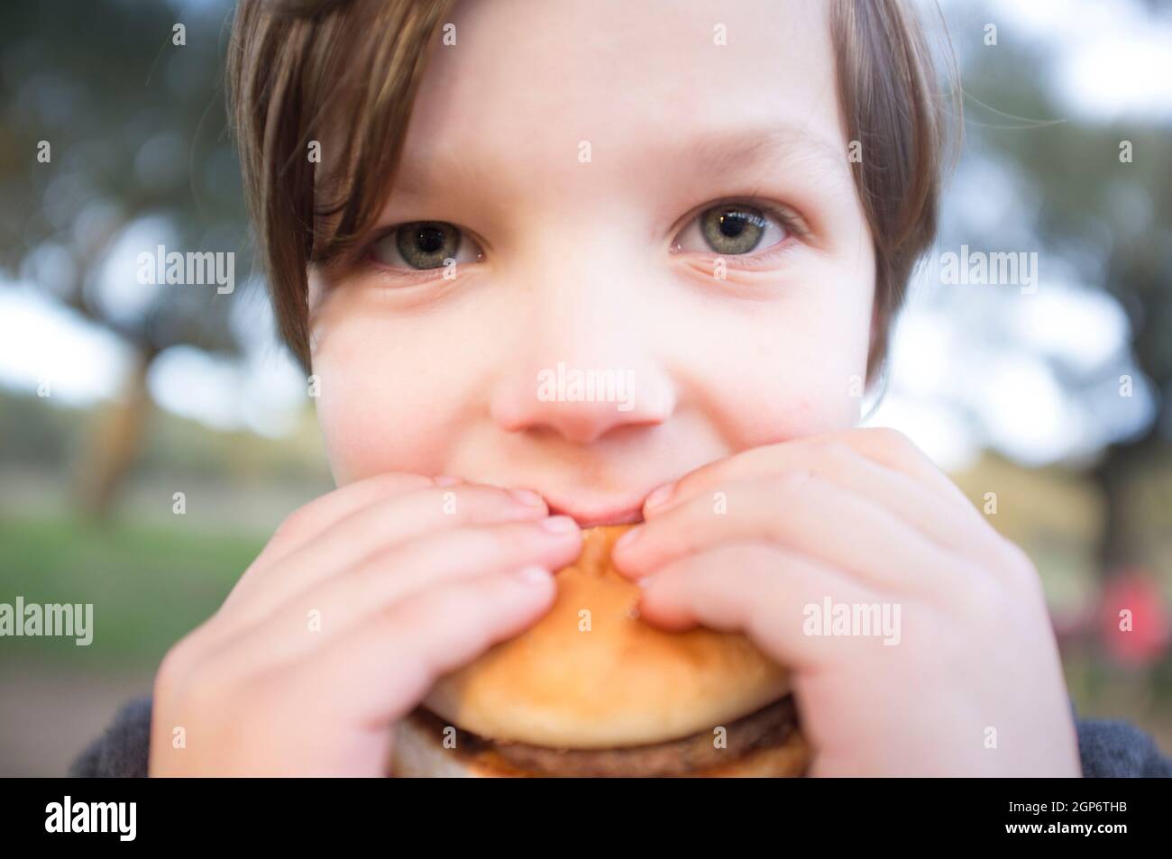 Little boy bites hamburger outdoors. Closeup Stock Photo - Alamy