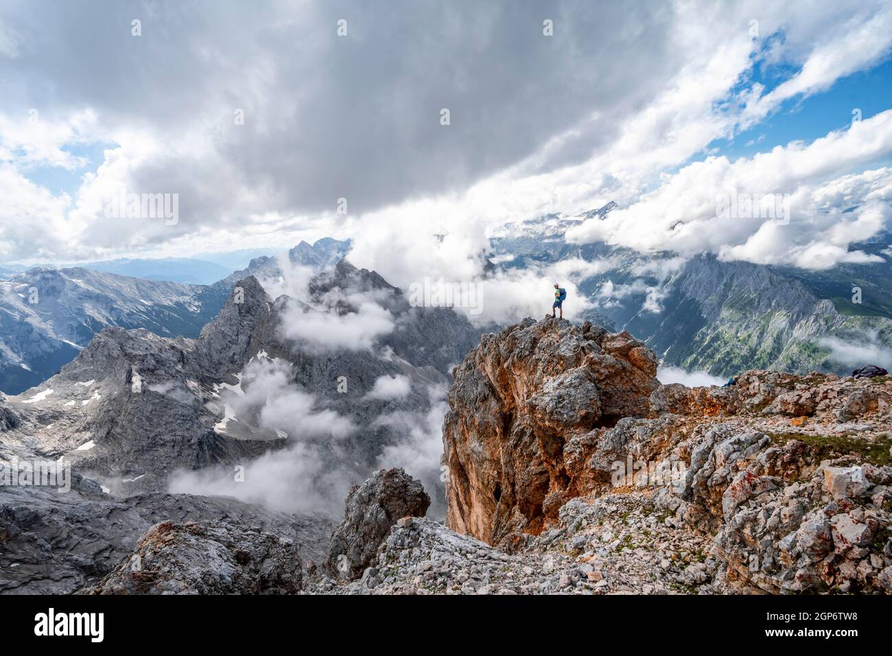 Hiker standing on a rock, at the summit of the Partenkirchner ...