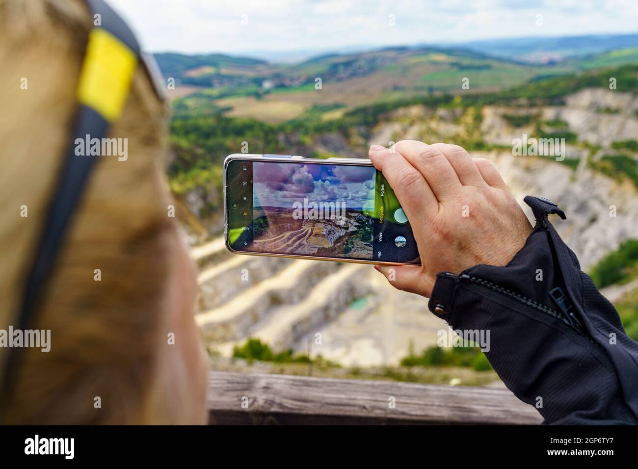 Worker taking a photo of a surface limestone mine with terraced stairs ...