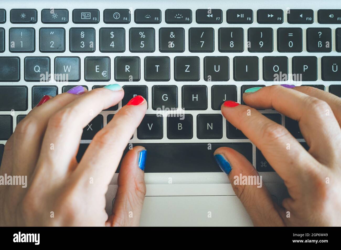 Woman fingers with colorful polished nails are typing on a laptop ...