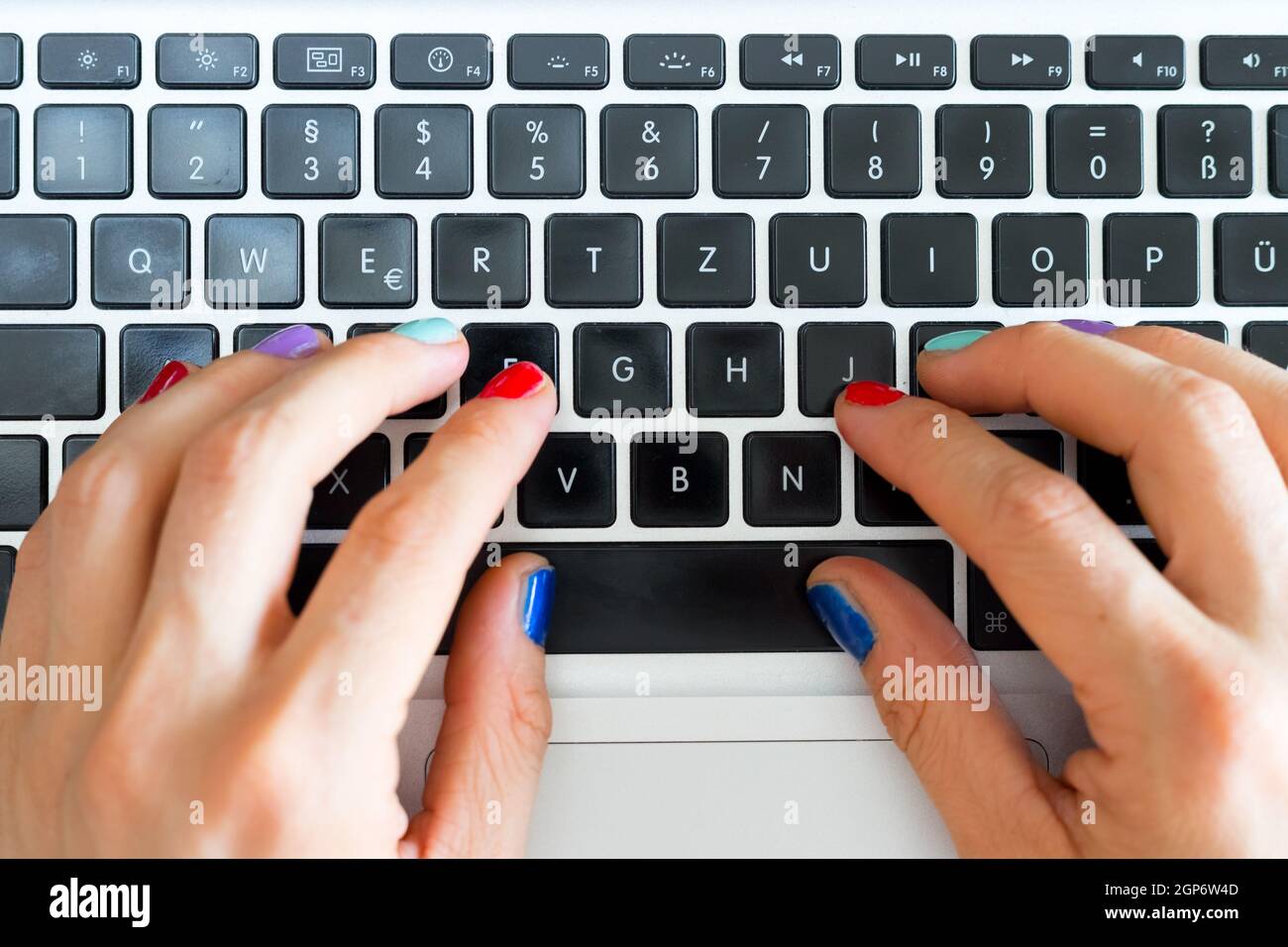 Woman fingers with colorful polished nails are typing on a laptop ...
