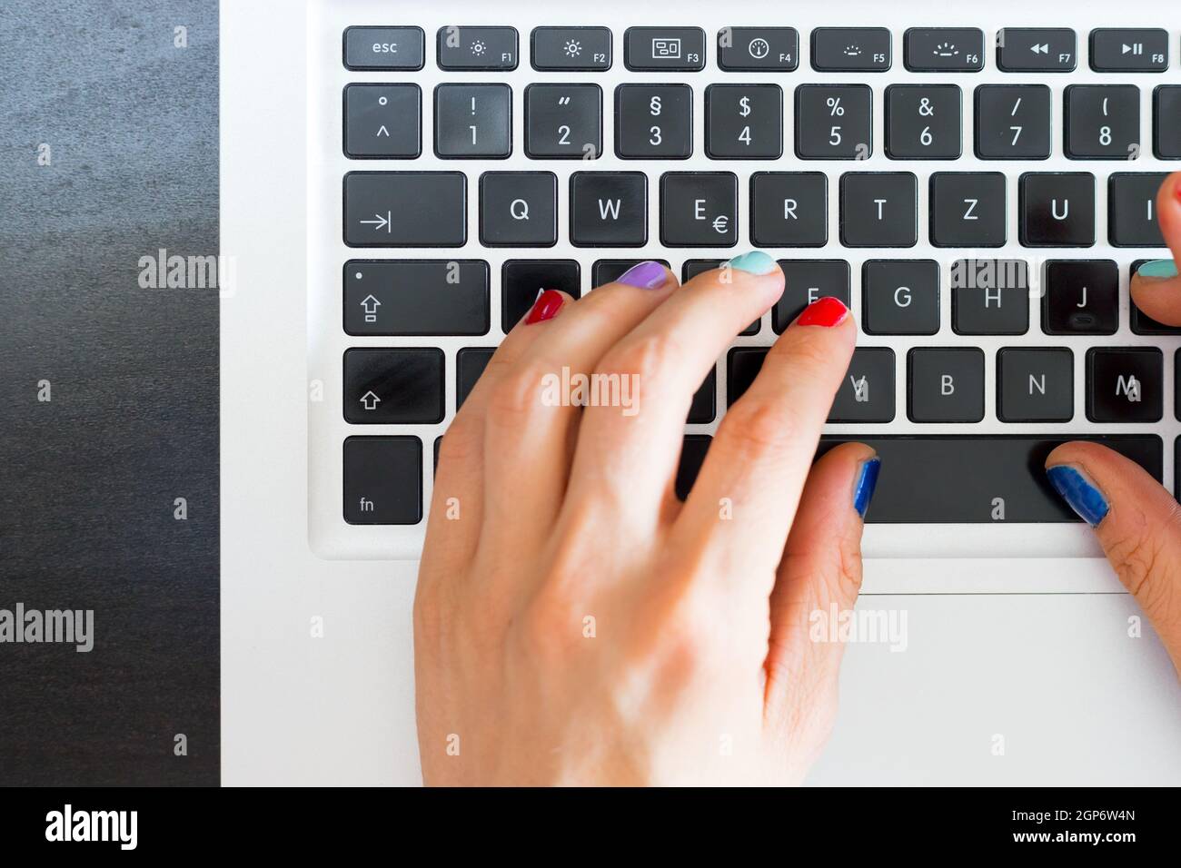 Woman fingers with colorful polished nails are typing on a laptop ...
