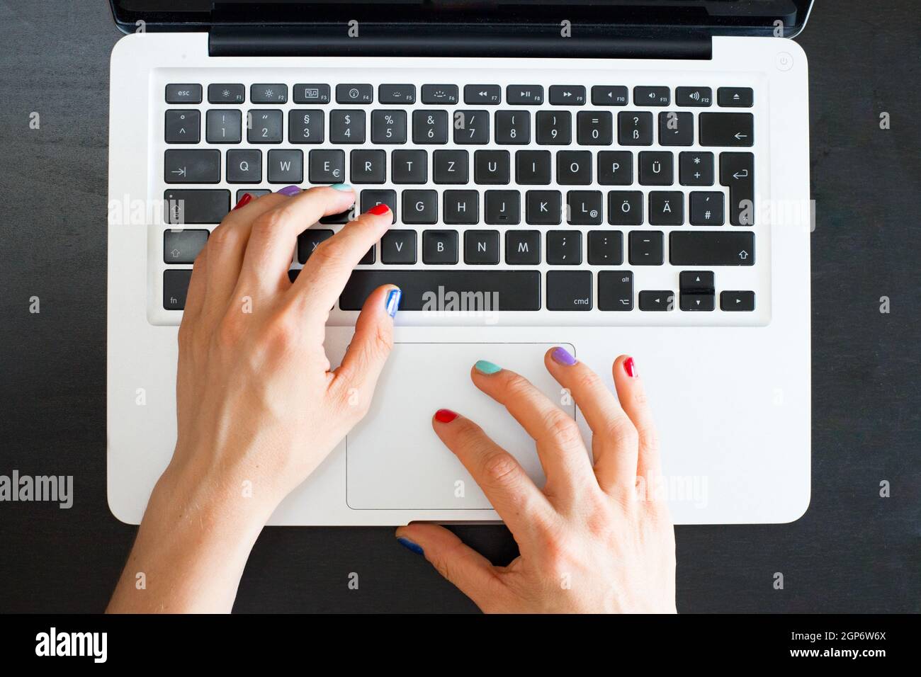 Woman fingers with colorful polished nails are typing on a laptop ...