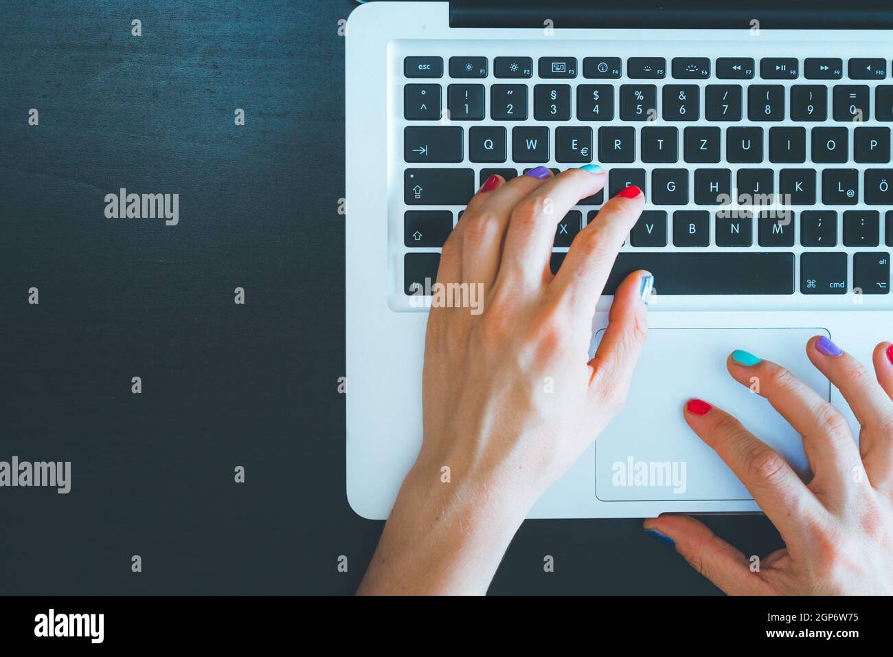 Woman fingers with colorful polished nails are typing on a laptop ...