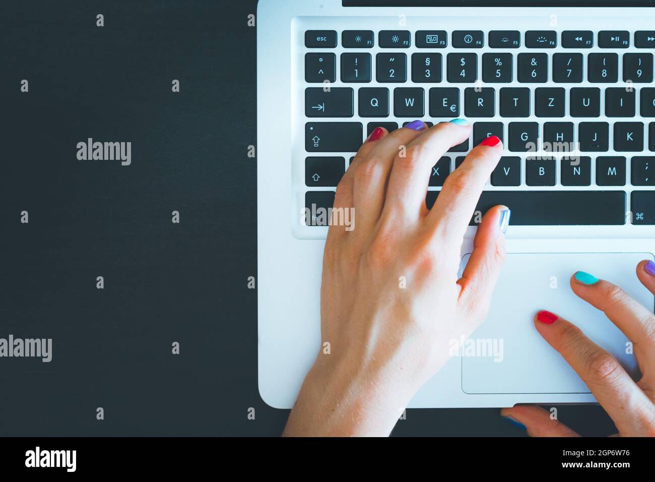 Woman fingers with colorful polished nails are typing on a laptop ...