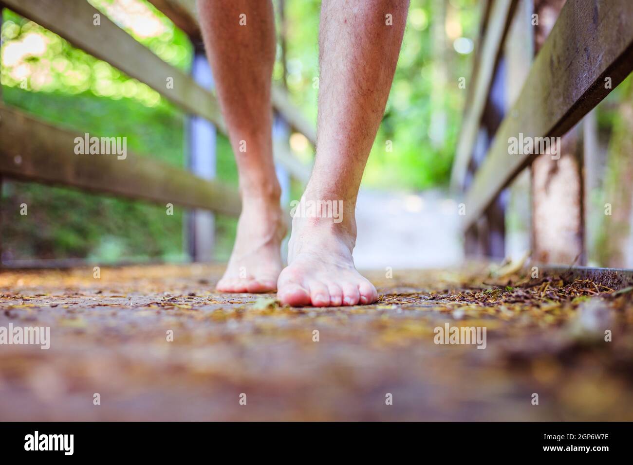 Barefoot feet on a rusty old wooden bridge in the forest, adventure ...