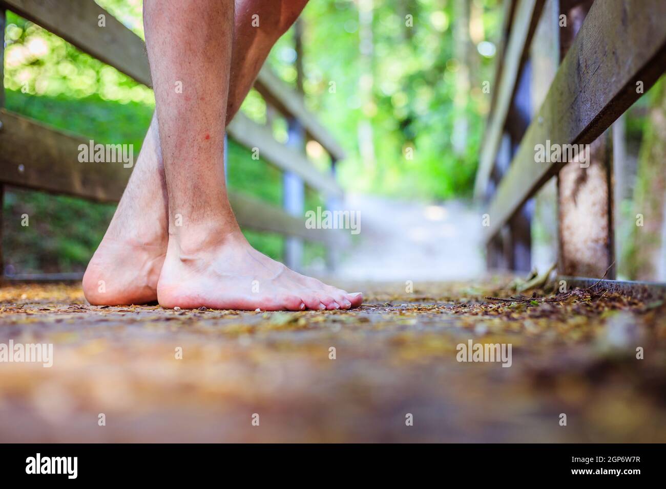 Barefoot feet on a rusty old wooden bridge in the forest, adventure ...