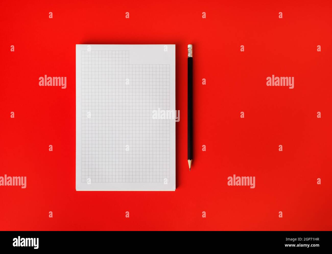 Blank copybook page and pencil on red paper background. Space for text ...
