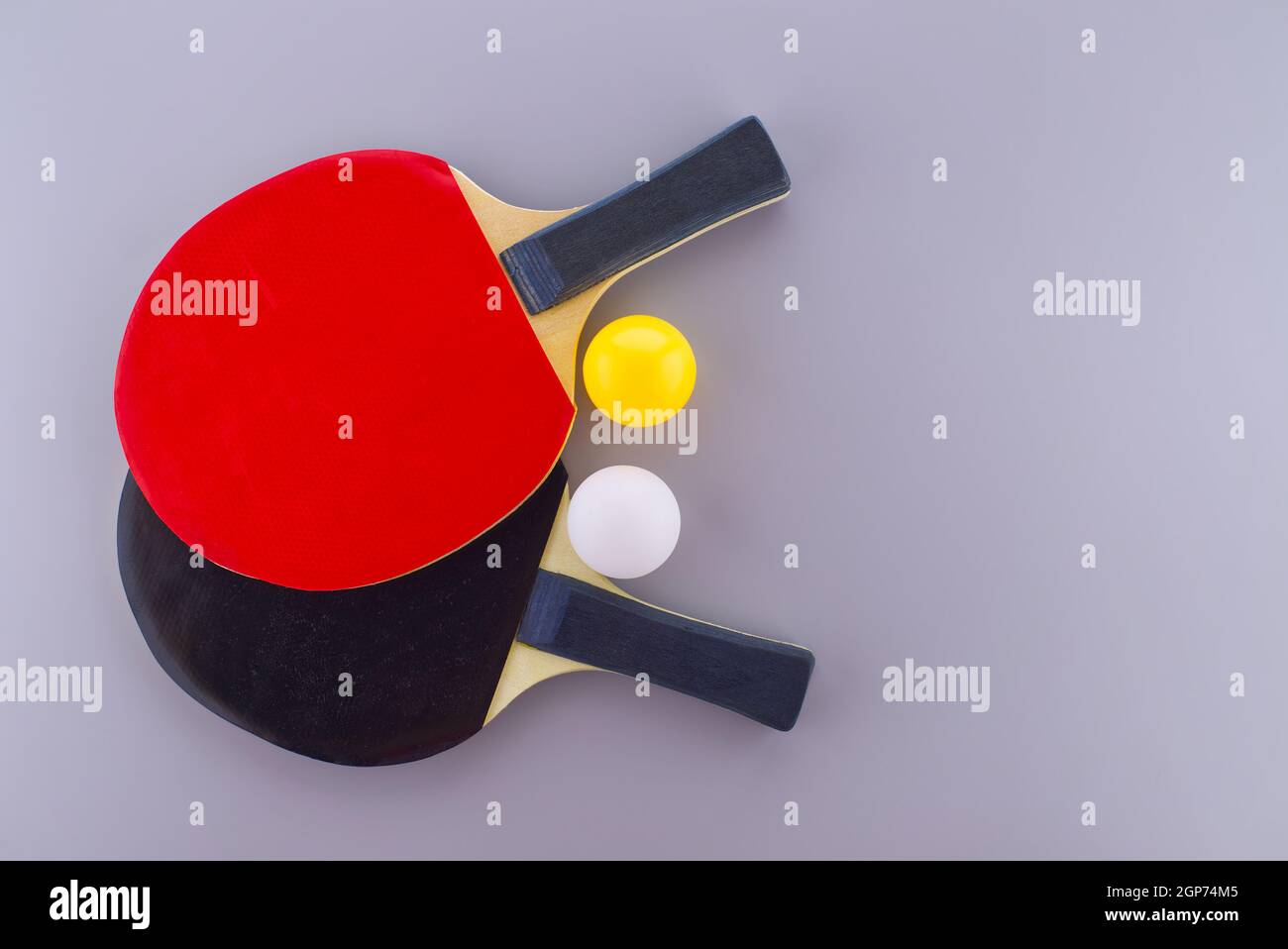 Red and black table tennis racks with a white and an yellow ping pong ...