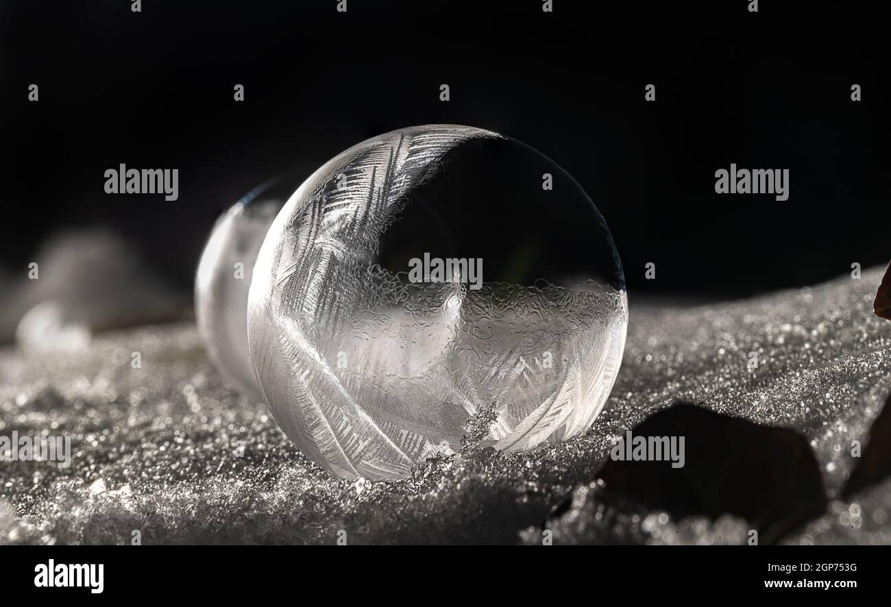 Detail shot of a frozen soap bubble on snow-covered ground against a ...