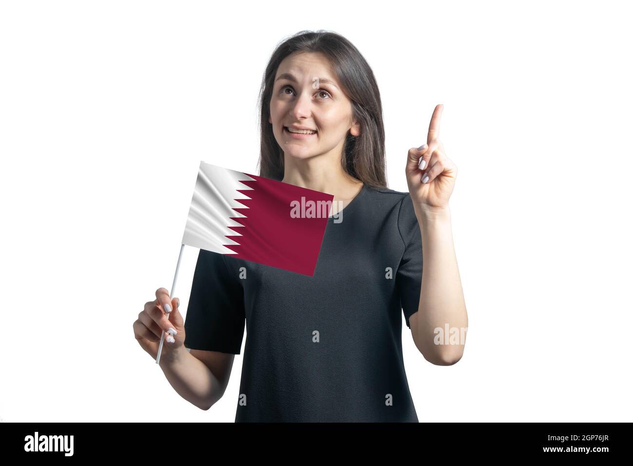 Happy young white woman holding flag of Qatar and points thumbs up ...
