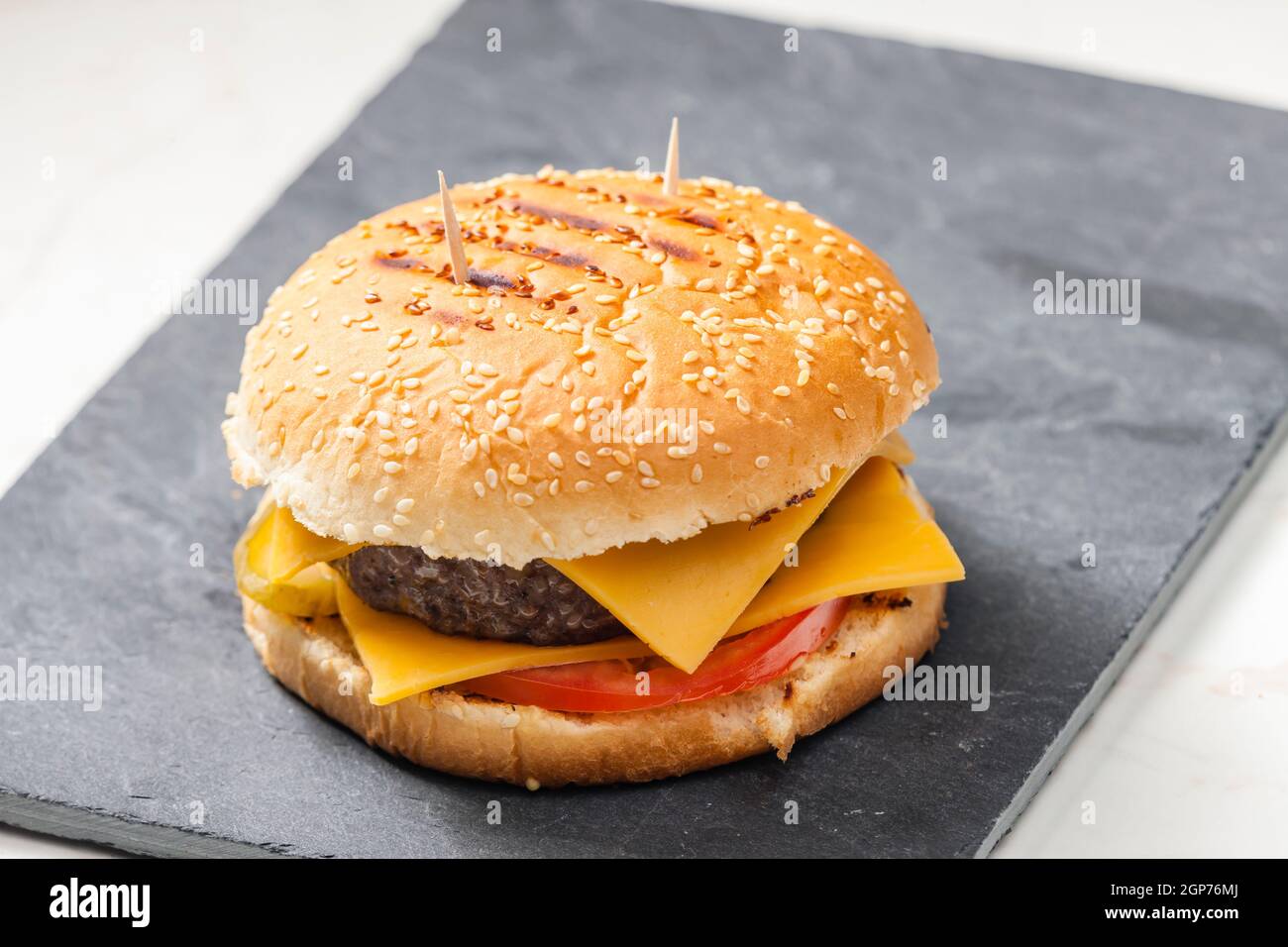 still life of cheeseburger on black plate Stock Photo - Alamy