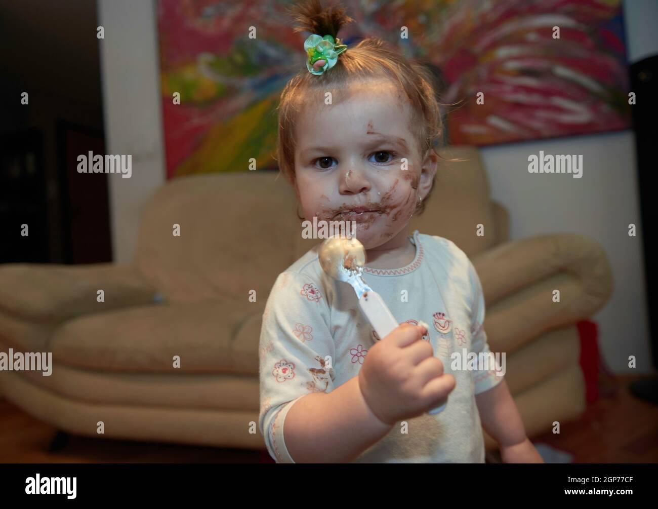 Cute little baby girl eating her chocolate desert after dinner with a ...