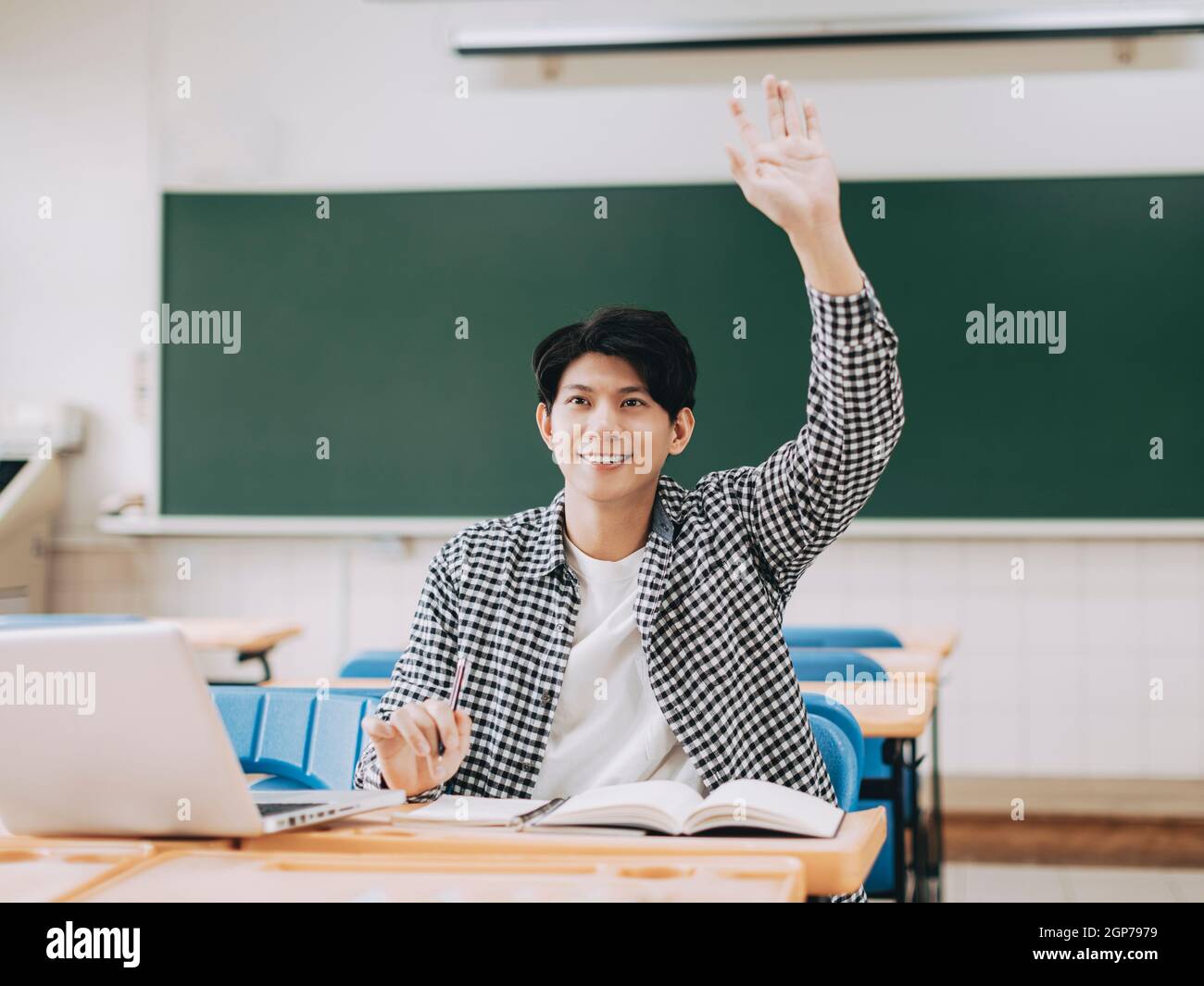 Young cheerful asian student raising hand in classroom Stock Photo - Alamy