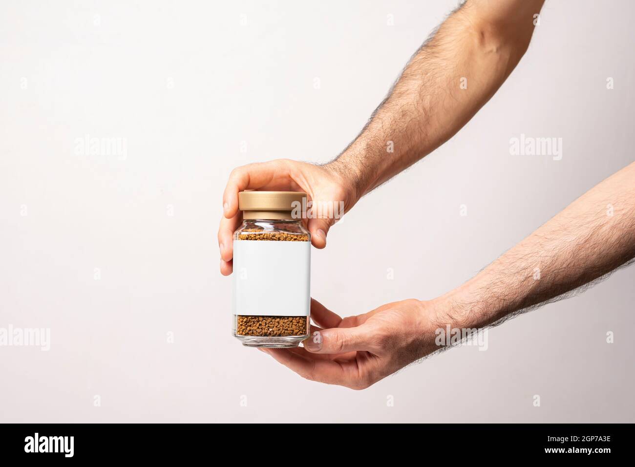 Male hand holding an instant coffee glass jar with blank label isolated ...