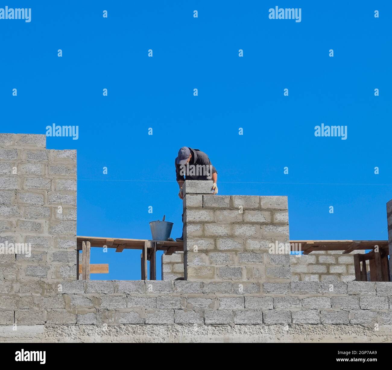 The builder builds the wall of the house from the cinder block. Worker ...