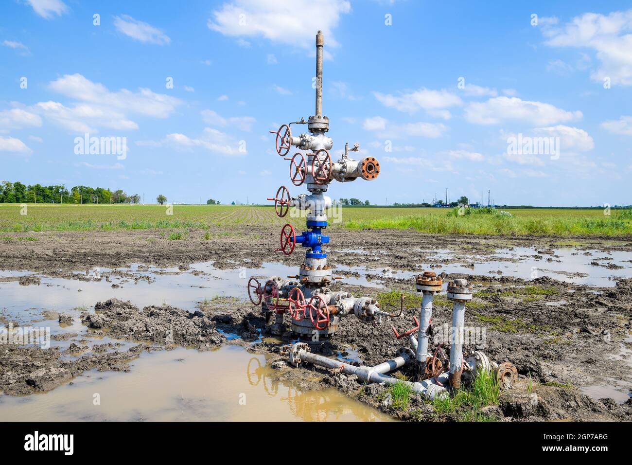 Oil well after repair in mud and puddles. Oil well wellhead equipment ...