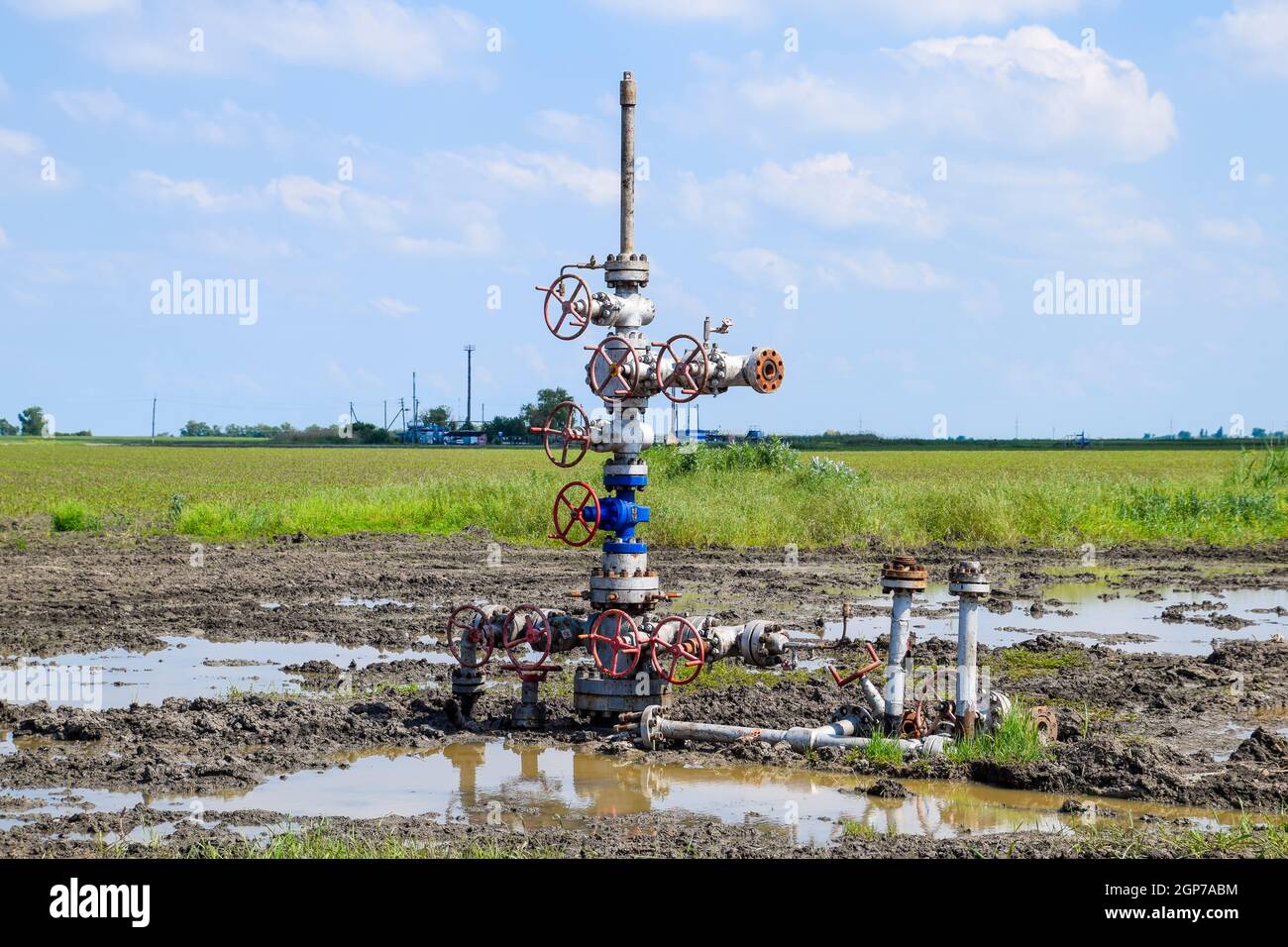 Oil well after repair in mud and puddles. Oil well wellhead equipment ...