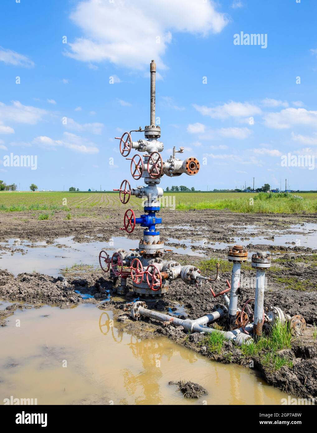Oil well after repair in mud and puddles. Oil well wellhead equipment ...