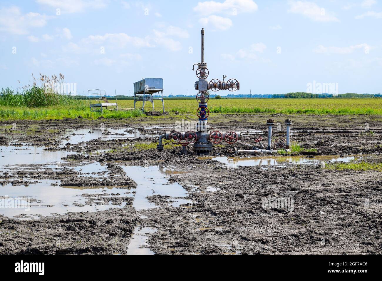 Oil well after repair in mud and puddles. Oil well wellhead equipment ...