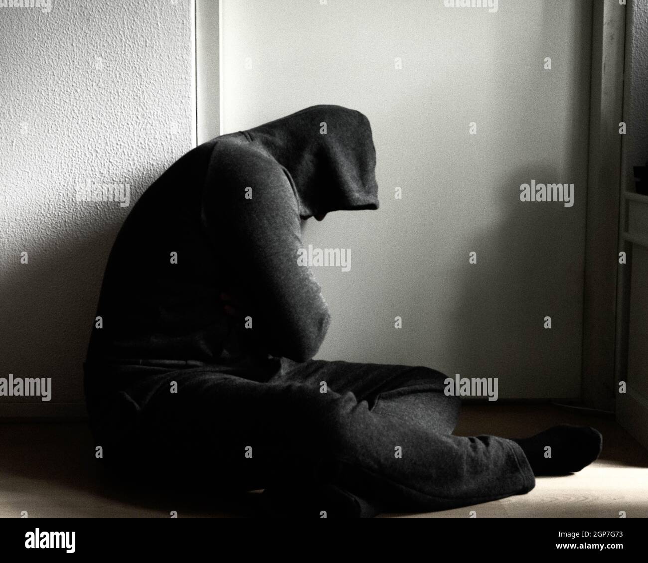 Depressed man sitting on the floor at home in front of a white ...