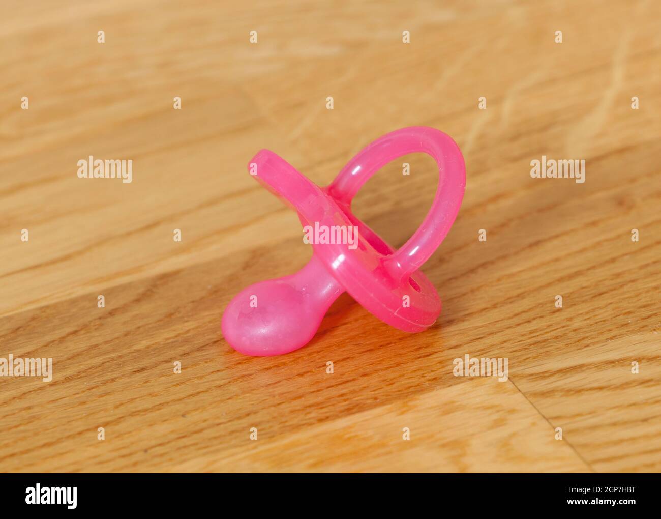 Pink baby pacifier lying on the parquet. Hygiene concept Stock Photo ...