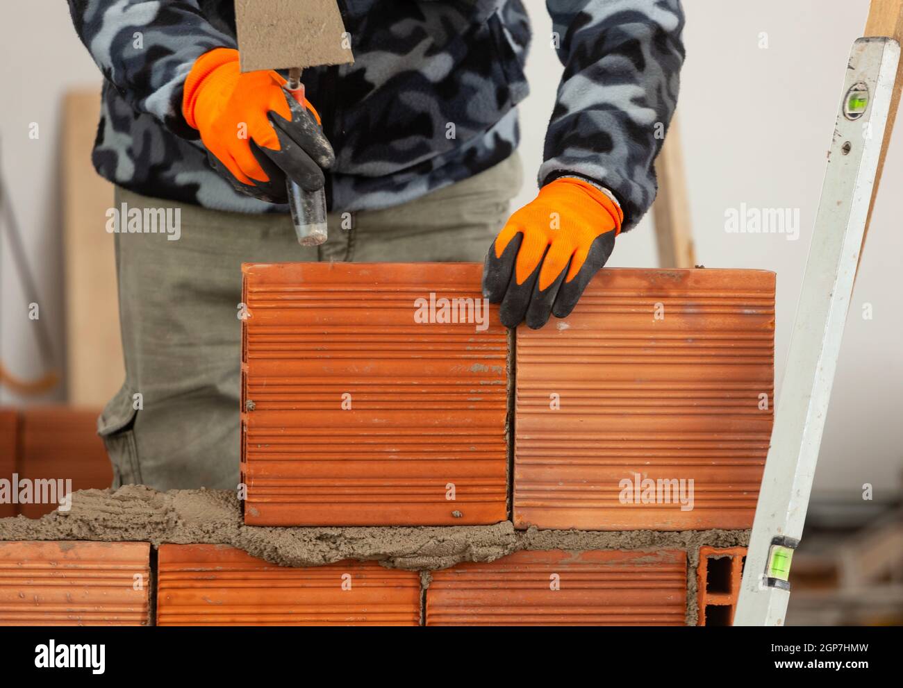 Bricklayer industrial worker installing brick masonry on interior wall ...