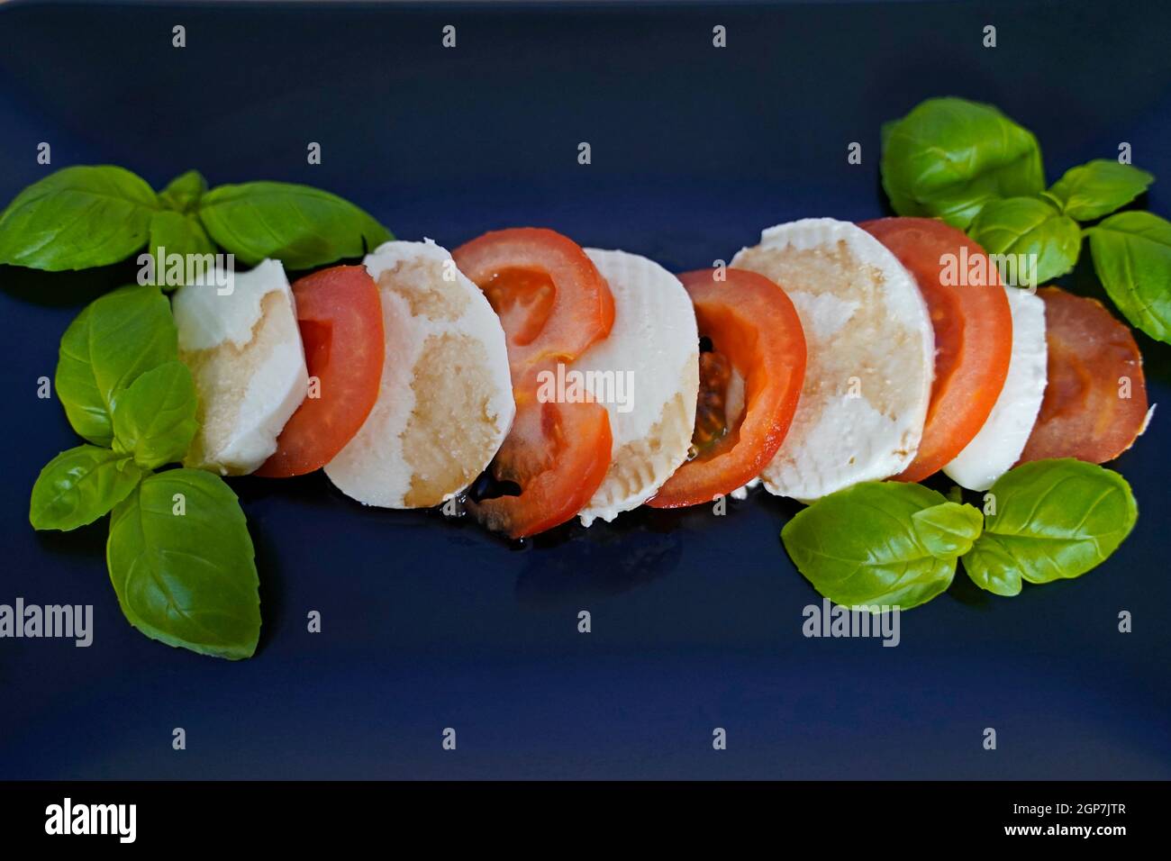 Tomato, basil and mozzarella with balsamic cheese arranged on black ...