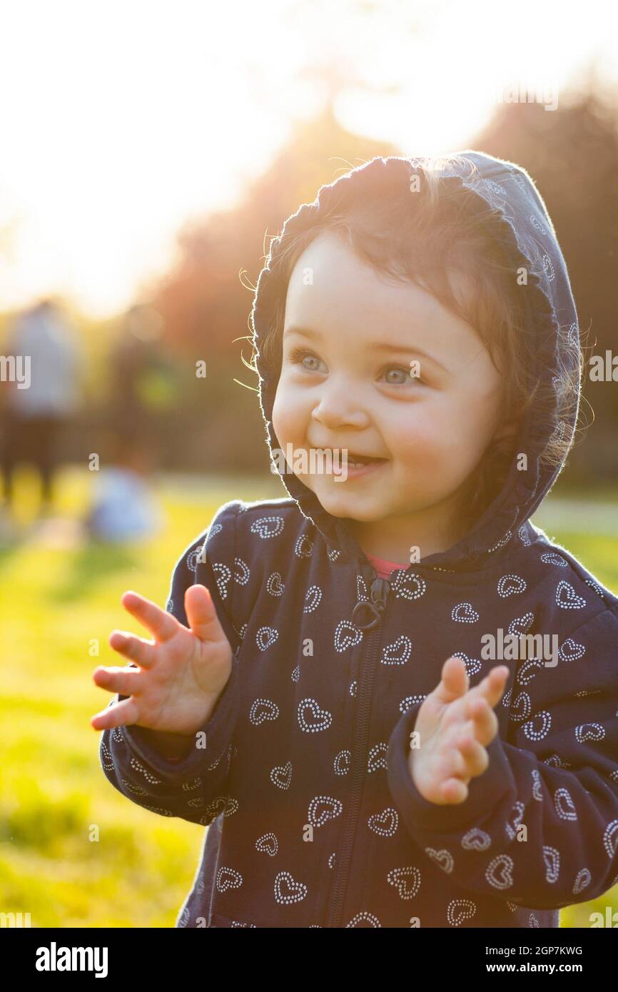 Little baby girl plays happy in the park outdoors in the spring in ...