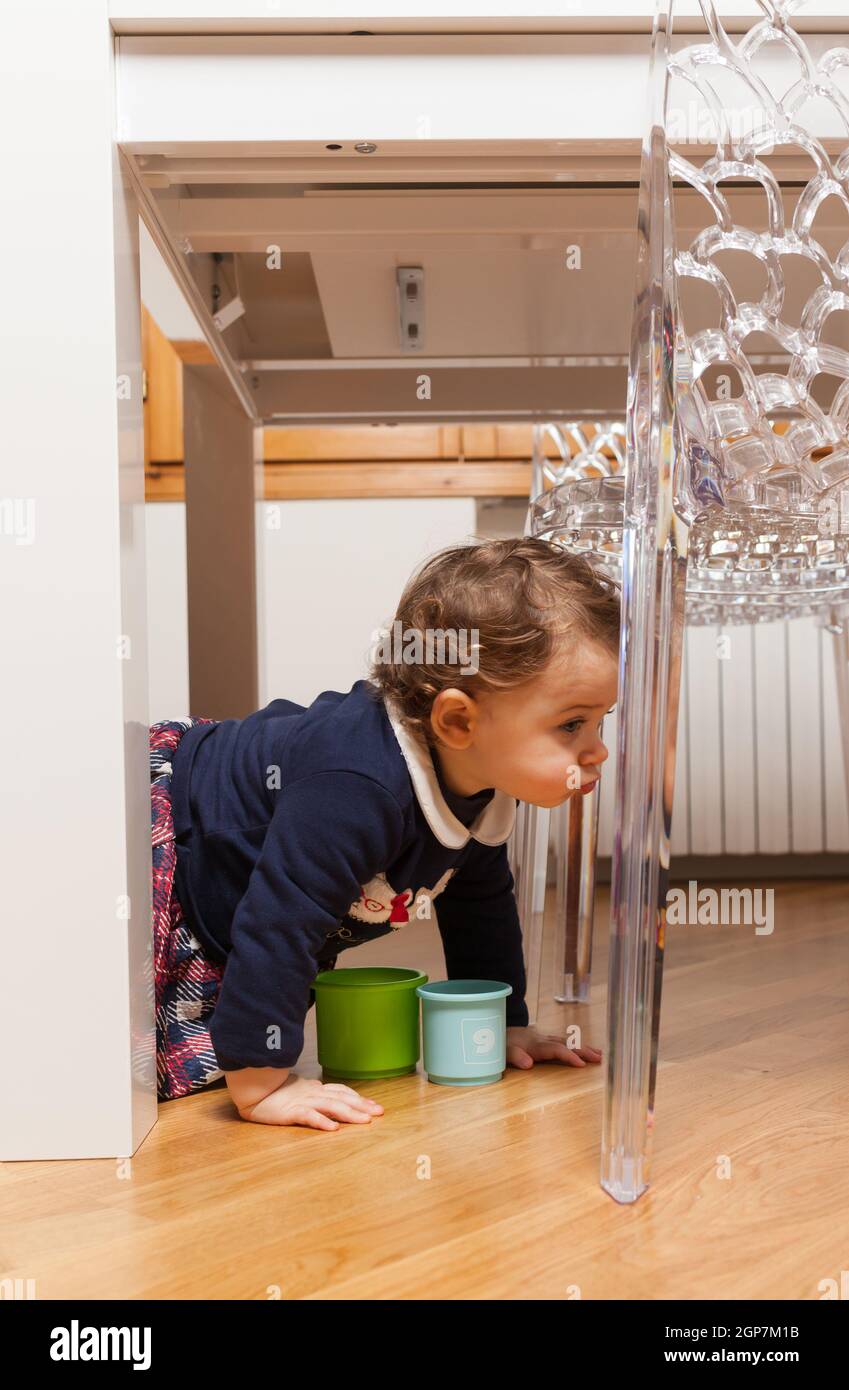 Toddler baby girl playing under the table. Concept of danger Stock ...