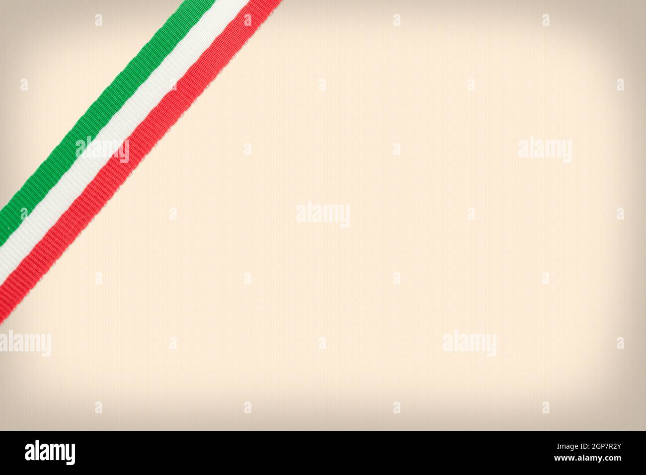 Tricolor ribbon of the Italian flag placed in the corner on beige ...