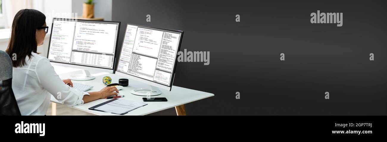 Computer Programmer In Office Using Multiple Monitor Screens Stock 