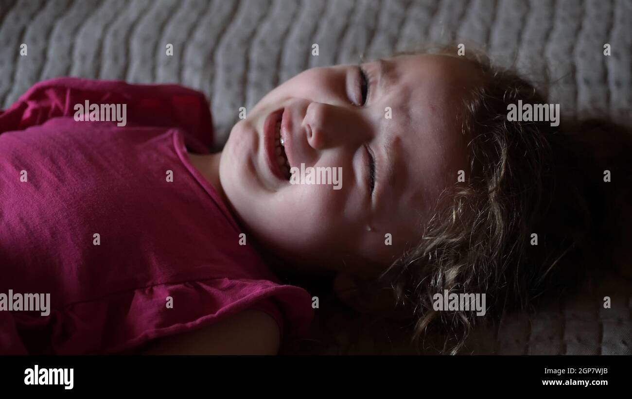 Three year old girl cries on the bed with soft light. Concept of ...