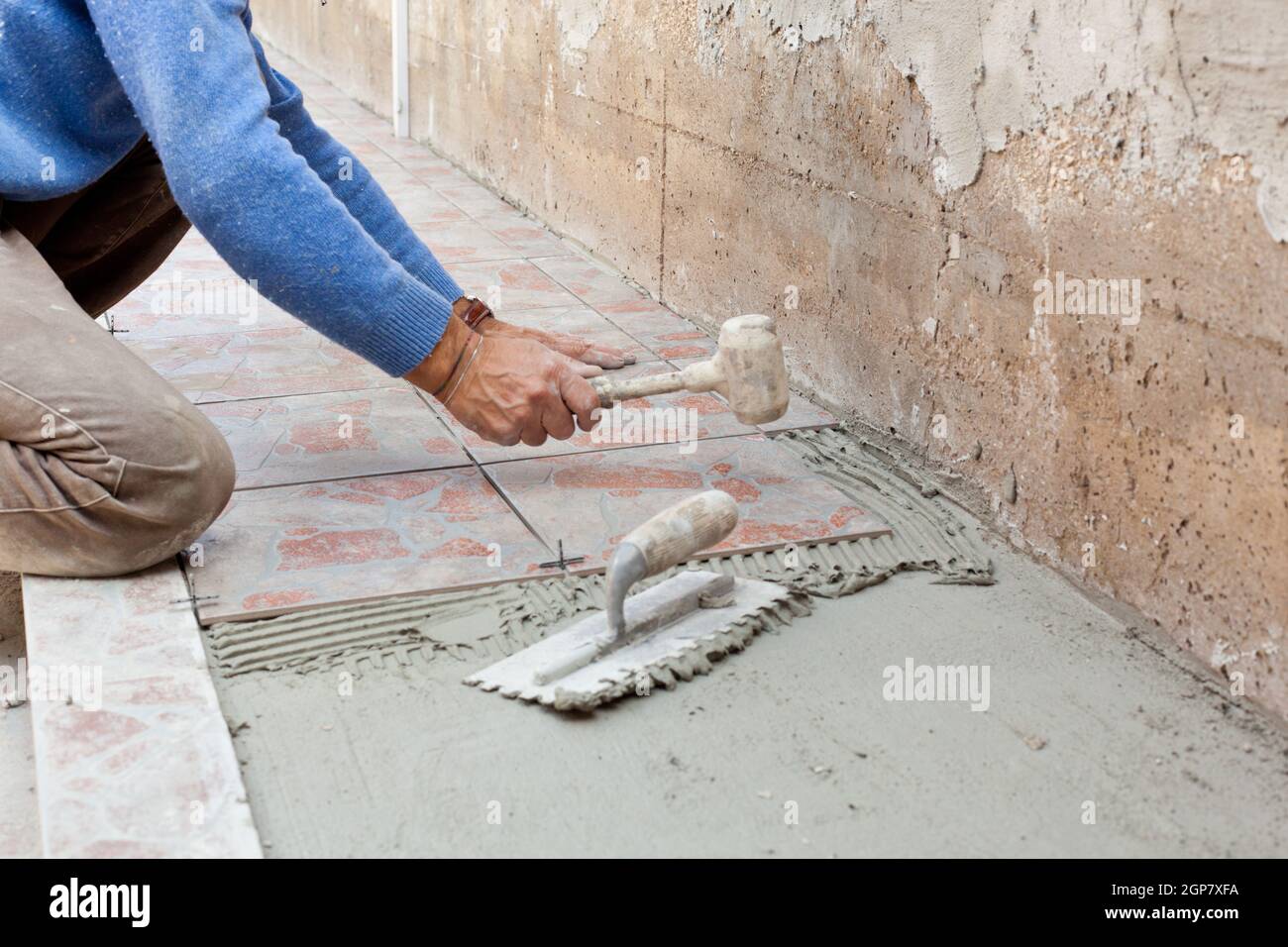 Tiler works with flooring in the backyard Stock Photo - Alamy