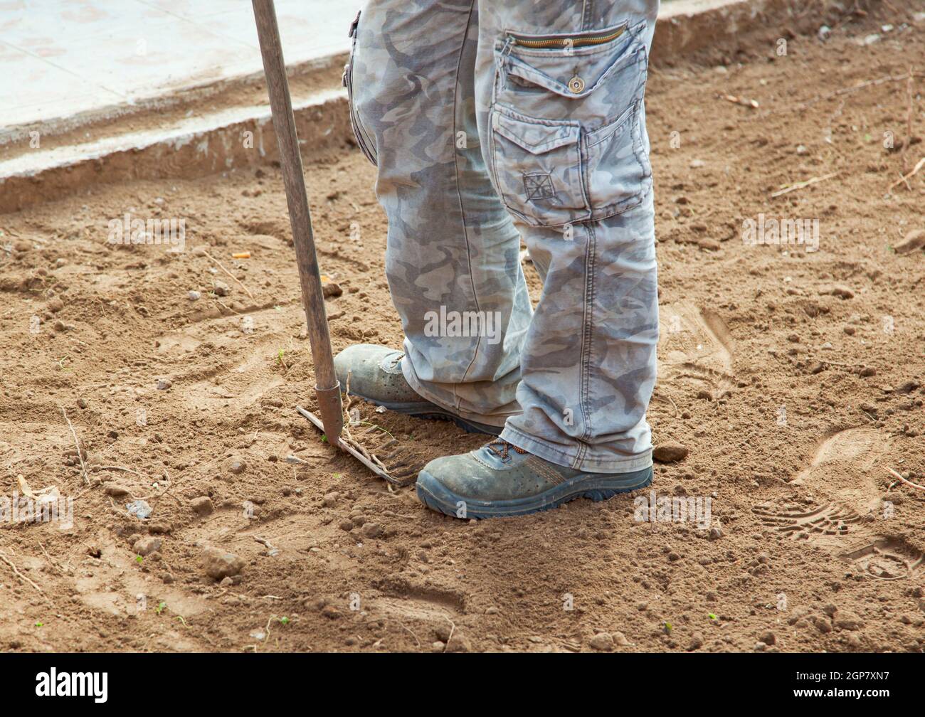 Worker with rake while crushing the ground in the yard Stock Photo - Alamy