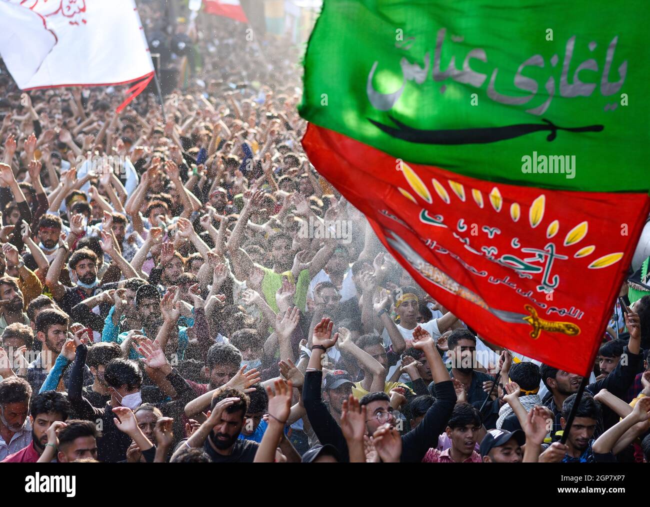 Shia Muslims wave religious flags and raise their hands during a ...