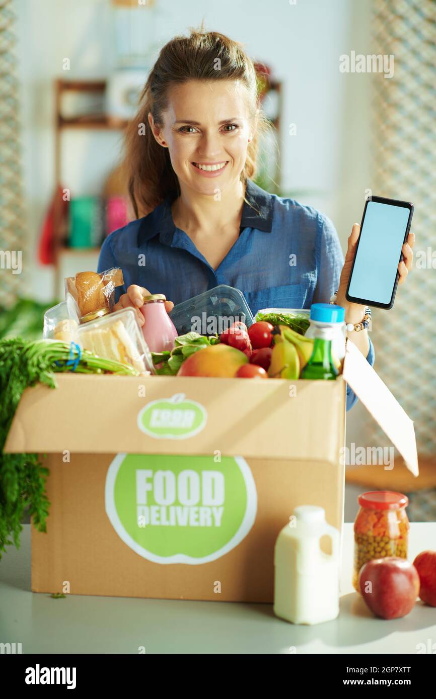 Food delivery. happy young female with food box showing smartphone ...