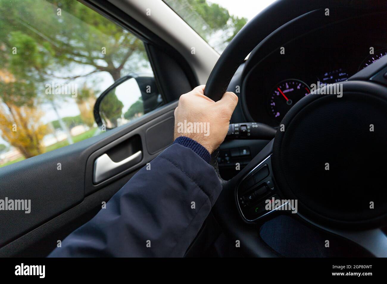 Man driving the car on the road holding the steering wheel with one ...